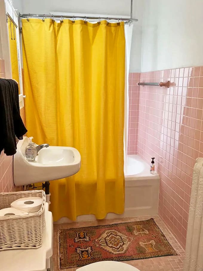 Even the bathroom brings whimsy with its pink tile and sunshine-yellow shower curtain – who says practical spaces can't have personality?
