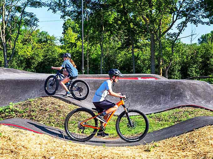 Riders tackle the pump track's rolling terrain &ndash; a symphony of momentum where the right rhythm means barely pedaling at all.
