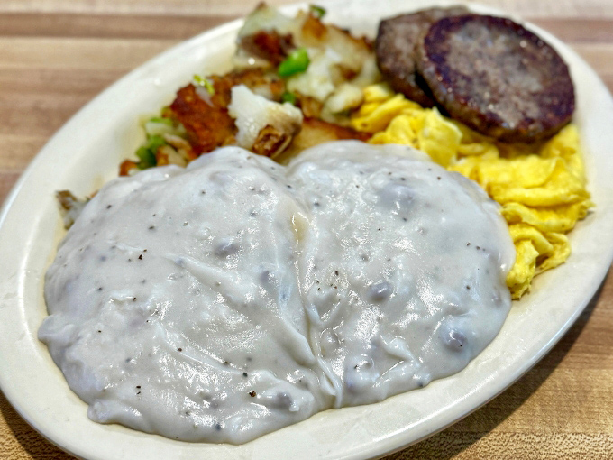 Biscuits and gravy – the comfort food equivalent of a warm hug from your favorite grandparent, with pepper-speckled gravy cascading over a golden-brown island.