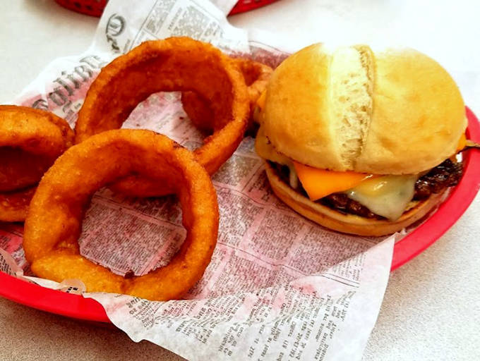 Golden onion rings so perfectly crisp they shatter like glass, nestled beside a burger that means serious business.