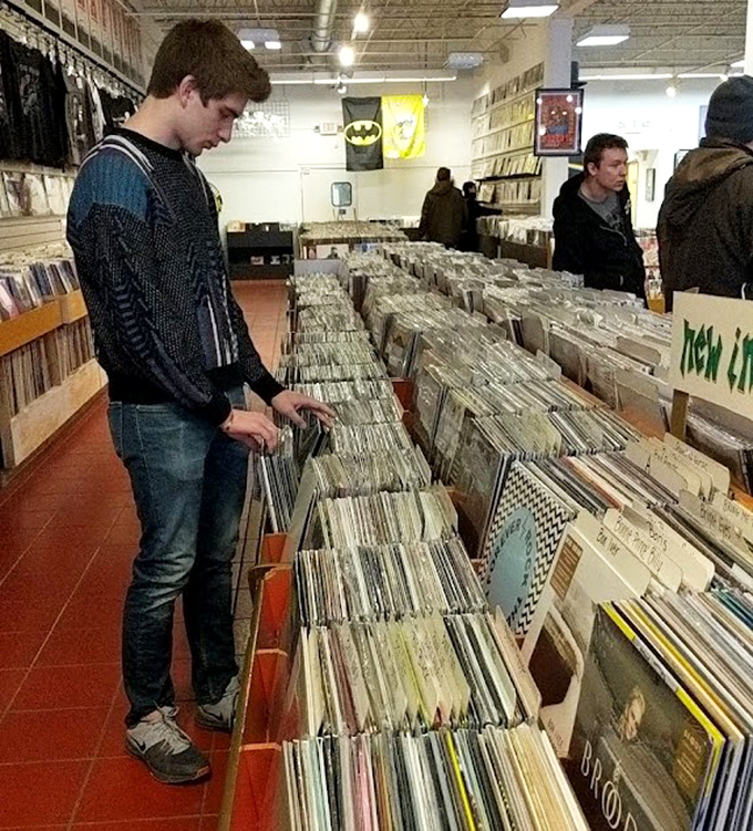 Customer at Vinyl Record Browsing Aisle: The sacred ritual of crate-digging &ndash; where time slows down and the thrill of discovery awaits in each sleeve.