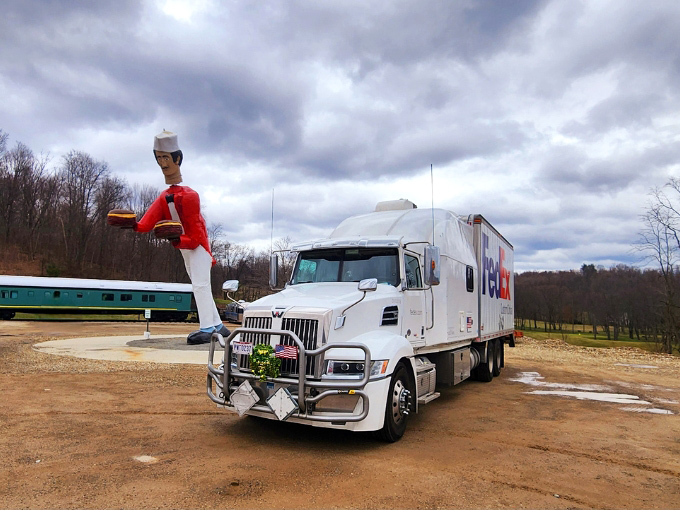 Even FedEx trucks look diminutive next to Chef Jacques, who towers over delivery vehicles like a nodding sentinel.
