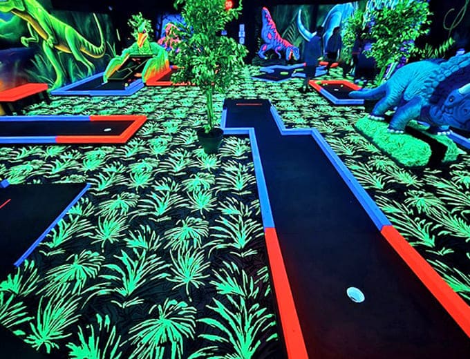 The meticulously designed course features glowing pathways that guide players through a jungle of neon obstacles and fluorescent challenges.