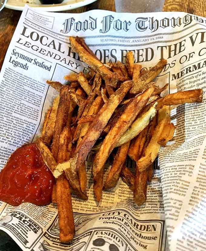 Hand-cut fries served newspaper-style &ndash; crispy, golden potato perfection that proves sometimes the simplest sides make the strongest statement.