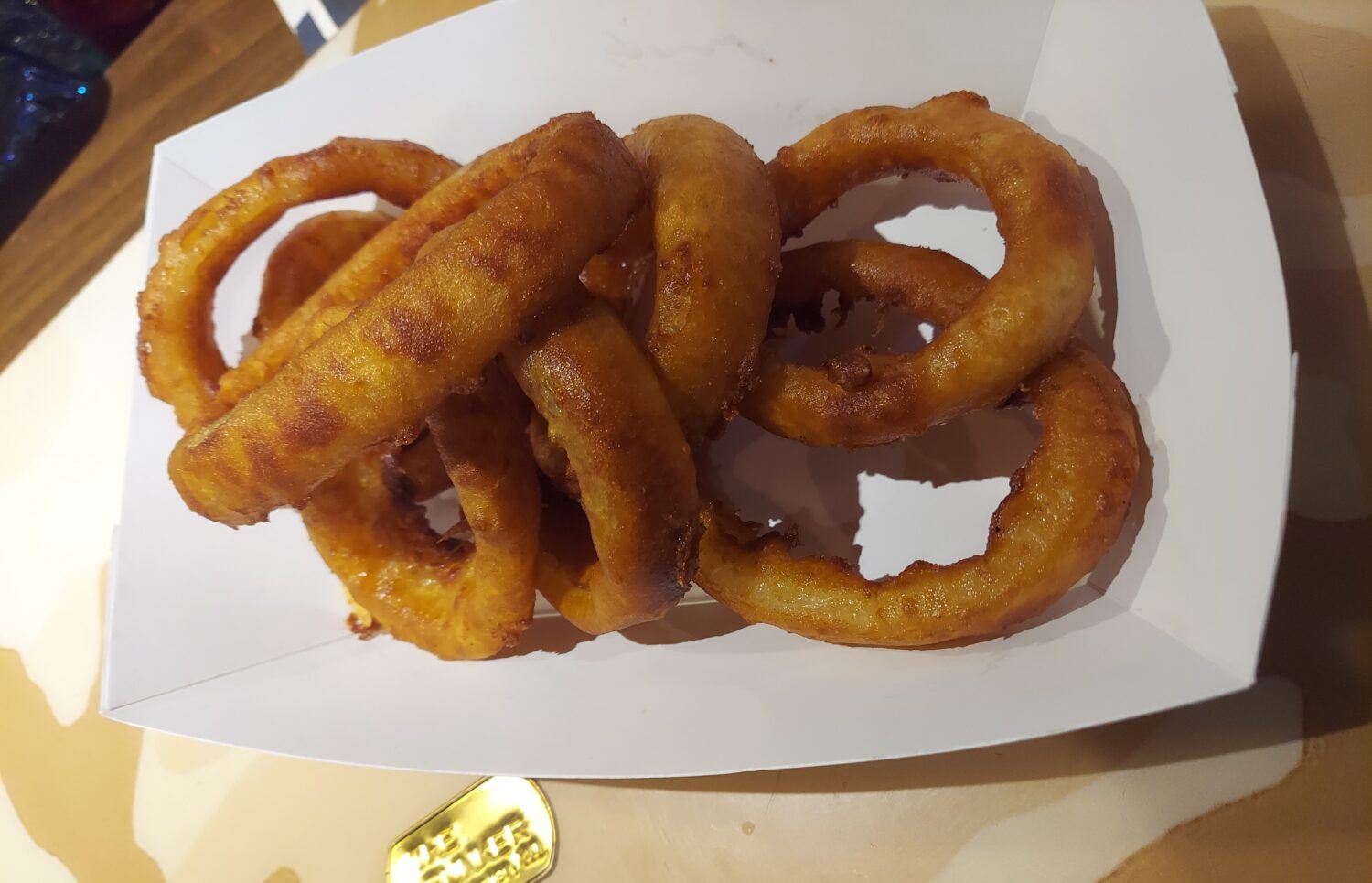Golden onion rings stacked like delicious life preservers &ndash; crispy, sweet, and the perfect companion to any sandwich on the menu.