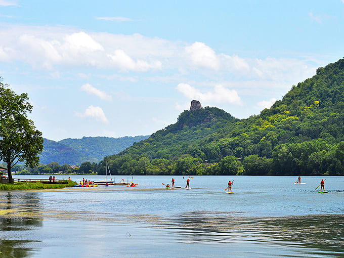 Adventurous souls find their zen on paddleboards, gliding across the Mississippi with Sugar Loaf Bluff standing sentinel in the distance.