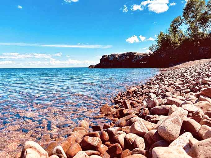 Crystal clear waters lap against the pink rhyolite shoreline, creating a contrast that photographers dream about.