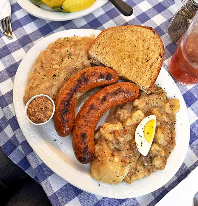 A hearty German plate featuring plump sausages alongside tangy sauerkraut and potato salad&mdash;comfort food that crosses all language barriers.