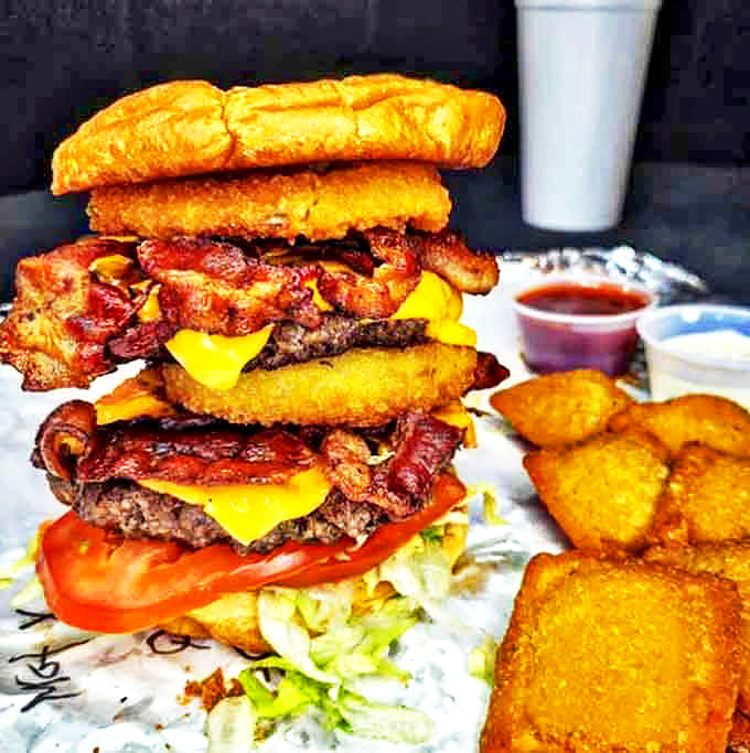 This towering creation defies both gravity and good sense, stacking bacon, cheese, and multiple patties into an edible skyscraper of deliciousness.