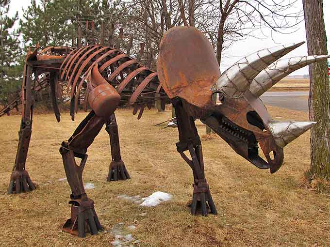 The triceratops stands guard with rusty dignity, its massive form showcasing how agricultural cast-offs can become Jurassic marvels.