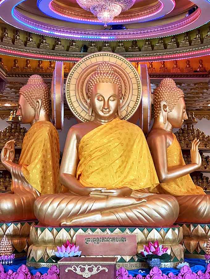 The triple Buddha display creates a mesmerizing effect &ndash; three perspectives of enlightenment catching the light from every angle in this sacred space.