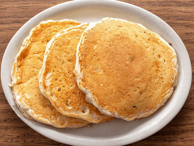 These aren't just pancakes; they're fluffy golden discs of joy stacked high enough to make you question your ability to finish them.