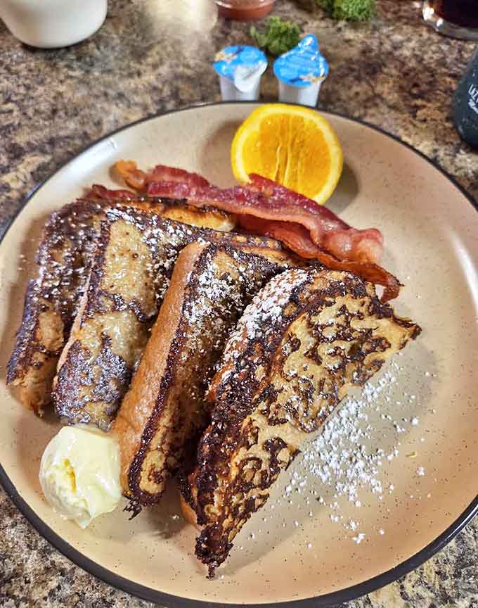 Golden-brown French toast dusted with powdered sugar and served with crispy bacon makes mornings at Lazy Moose something to anticipate.