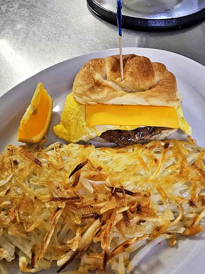Breakfast sandwich heaven on a croissant with perfectly crispy hashbrowns. The orange slice isn't just garnish&mdash;it's nature's palate cleanser!