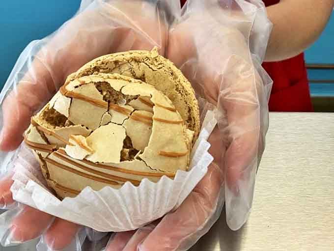 Cookie sandwich architecture at its finest &ndash; layers of sweet engineering held by gloved hands that understand the gravity of their mission.