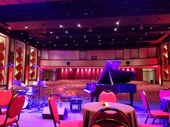 A grand piano waits in the spotlight, ready for jazz notes to fill the air in a space where music feels more alive than recorded.