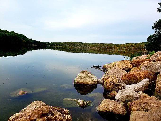 Lake Mallalieu's glassy surface perfectly mirrors the surrounding landscape, creating a moment of serenity away from the falls' constant motion.