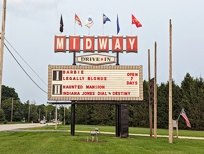 The marquee announces tonight's features, flags fluttering above like a celebration of cinema under open skies.