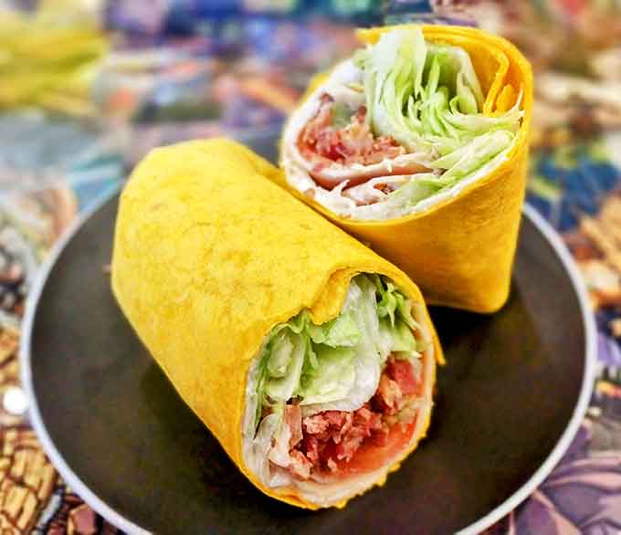 BLT Wrap: Bright yellow tortilla hugs fresh ingredients like a superhero's embrace &ndash; portable, practical, and packed with flavor-fighting power.