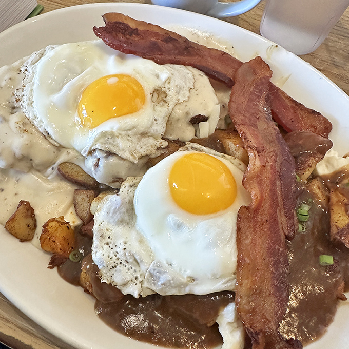 Breakfast architecture at its finest – eggs perched atop a foundation of potatoes, all blanketed in that famous gravy.