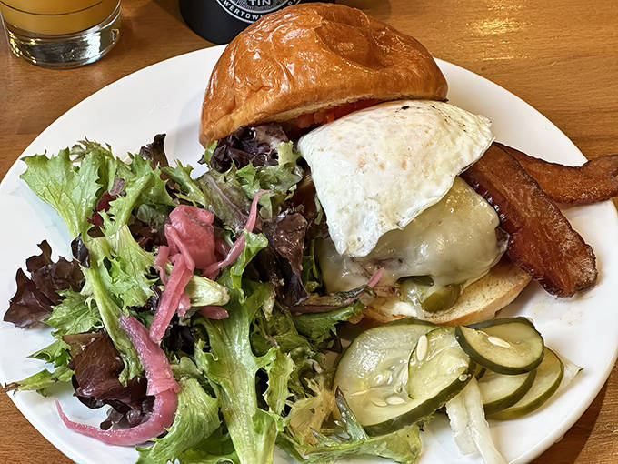 The breakfast burger arrives like a tower of morning indulgence &ndash; melted cheese, bacon, and that perfect sunny-side-up egg crowning the throne.
