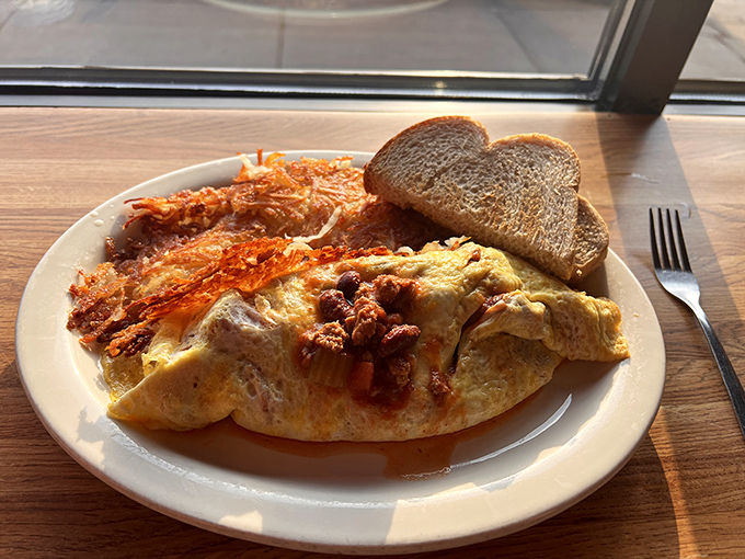 A classic diner breakfast: fluffy omelet, crispy hash browns, and toast – simple perfection that needs no embellishment or fancy plating.
