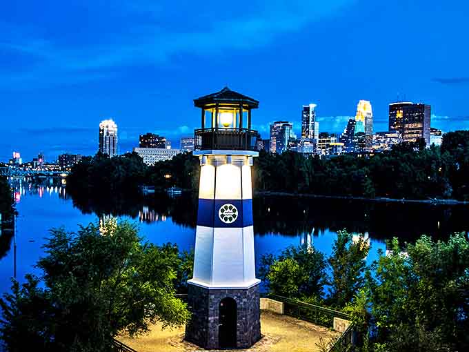 As night falls, the lighthouse glows against the illuminated Minneapolis skyline, creating a magical scene worthy of any postcard.