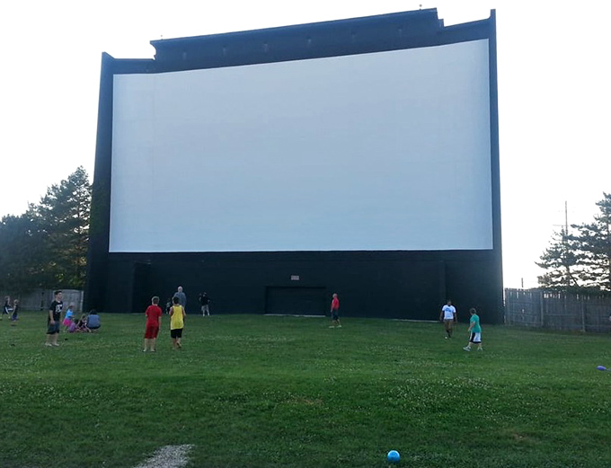 Children play impromptu games of tag beneath the towering screen, burning energy before settling in for the feature presentation.