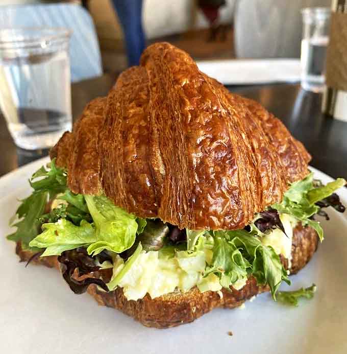 Croissant architecture at its finest – layers of buttery pastry creating the perfect vessel for fresh greens and creamy egg salad.