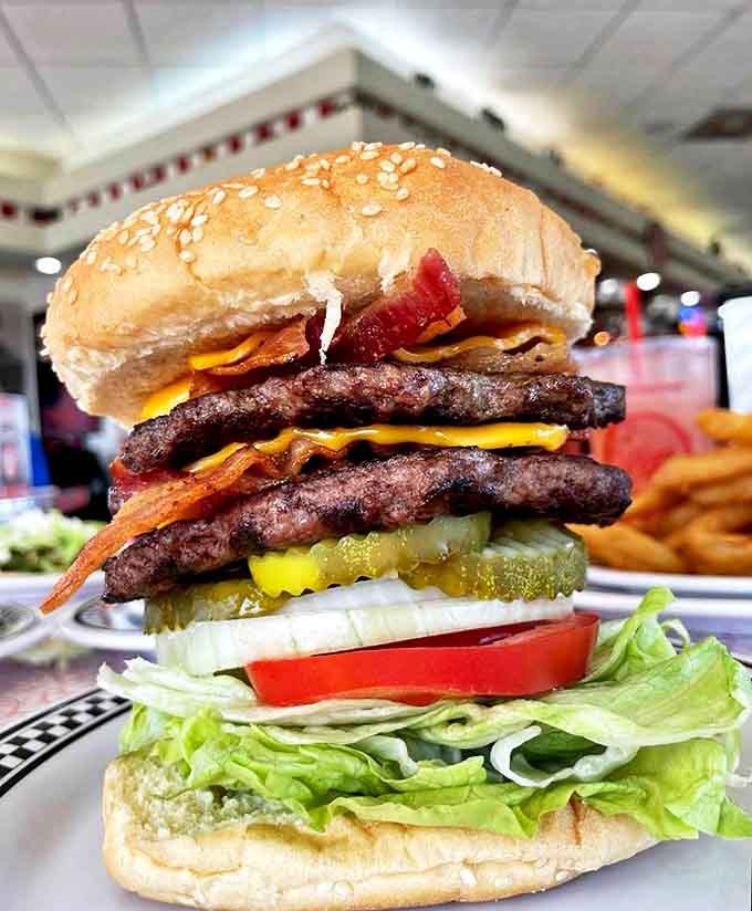 This burger towers like a delicious skyscraper, complete with bacon, cheese, and enough toppings to require structural engineering.