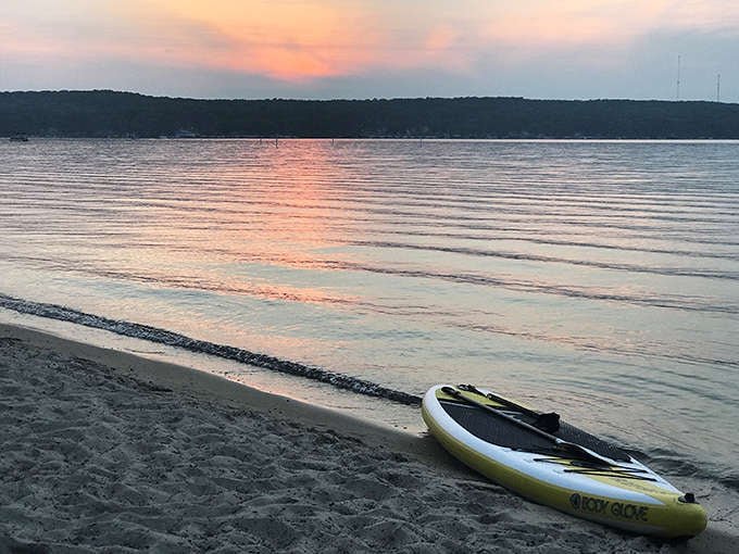 Sunset paddleboarding on Higgins Lake &ndash; where "finding your balance" takes on both literal and metaphorical meaning.