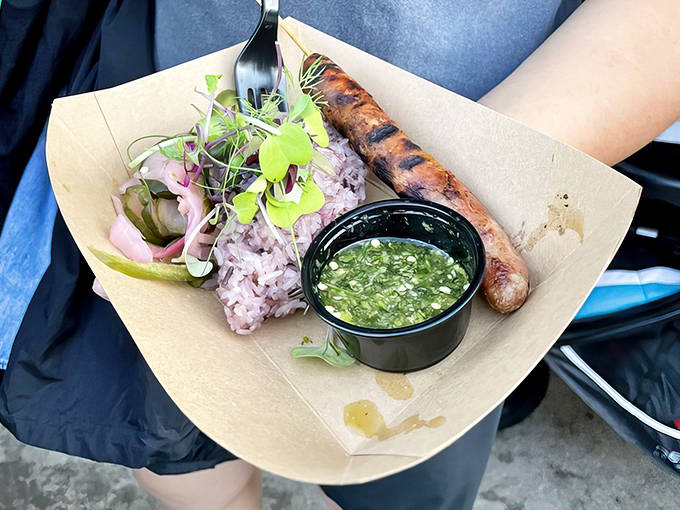 A perfect harmony of flavors &ndash; Hmong sausage nestled beside purple sticky rice with chimichurri sauce creates a cross-cultural culinary masterpiece.