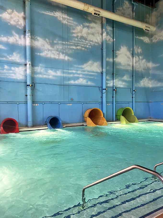 Colorful tubes emerge from the wall like giant straws, delivering riders into the crystal-clear waters below after thrilling journeys through enclosed darkness.