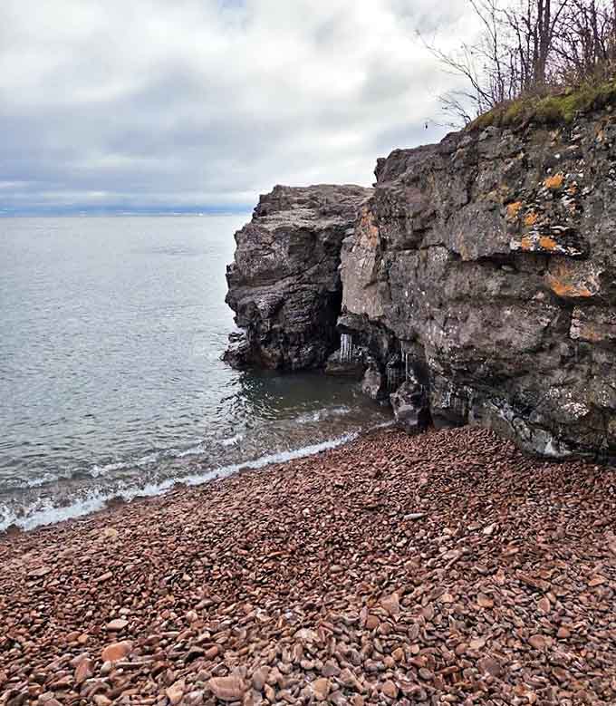 Dramatic cliffs stand sentinel over the beach, slowly surrendering more pink stones to join the chorus below.