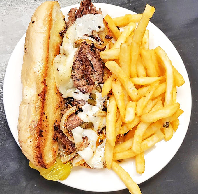 A hearty sandwich that would make Philadelphia proud, nestled beside fries that achieve the perfect crisp-to-fluffy ratio.