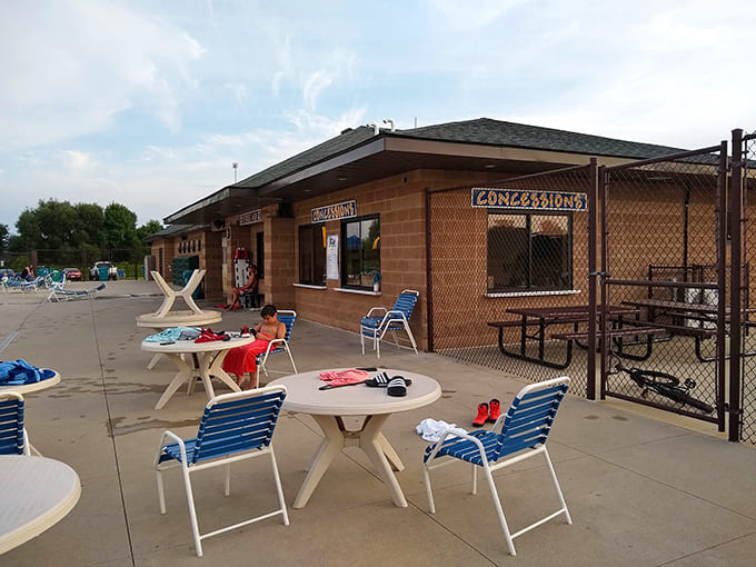Those poolside tables where families claim territory and parents guard the snacks like dragons protecting treasure.