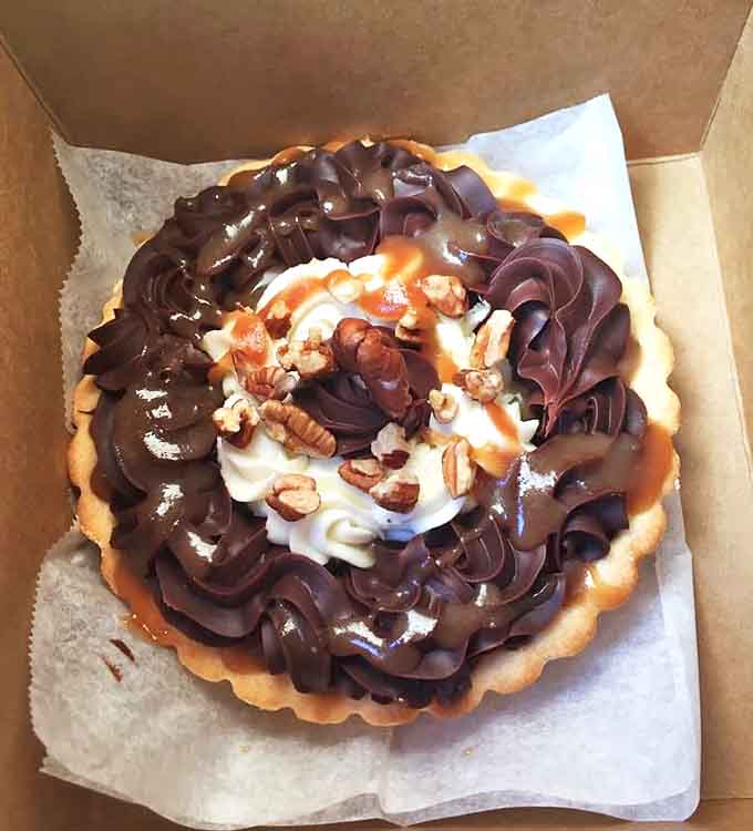 Chocolate and caramel perform their eternal dance atop this turtle tart, with pecans adding textural applause to every decadent bite.