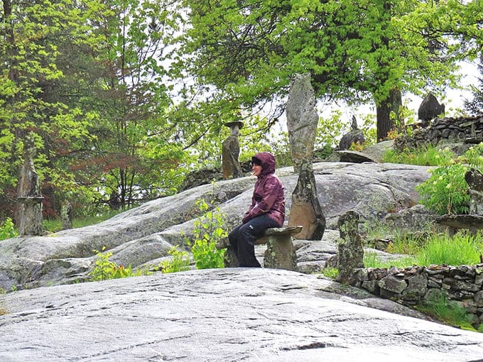 A visitor finds contemplative solitude on a stone bench, surrounded by rock formations that have stood sentinel through decades of Minnesota's dramatic seasonal changes.