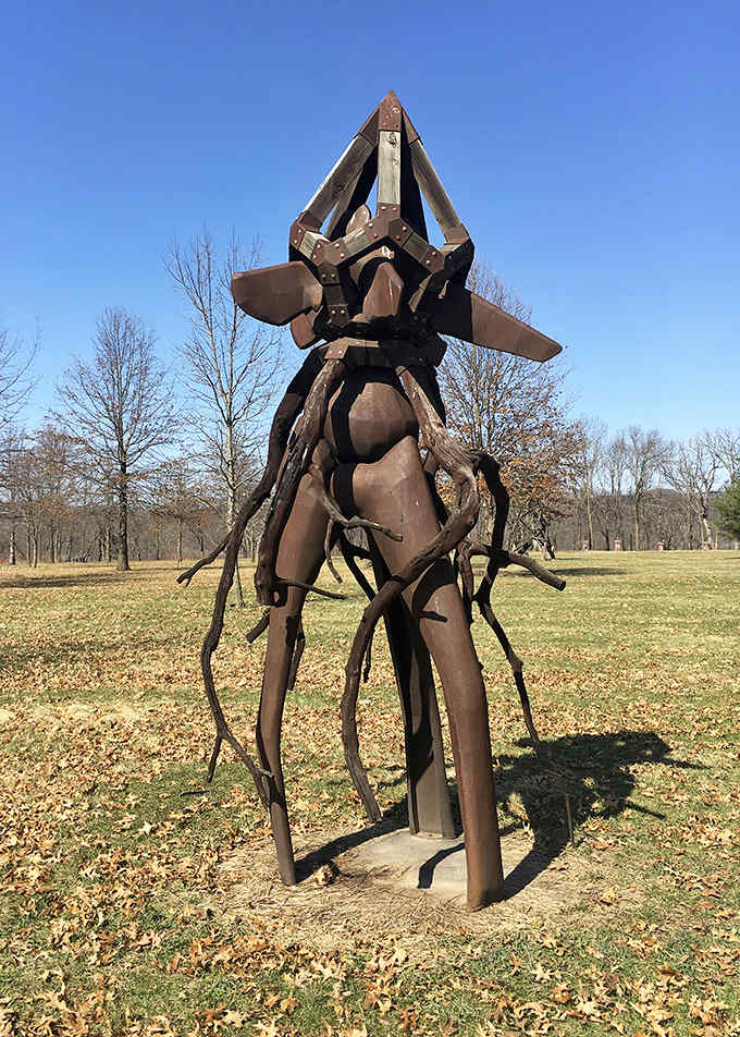 Weathered iron forms create a figure that seems both ancient and futuristic, standing sentinel over the peaceful grounds.