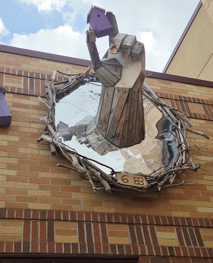 A wooden hand emerges from a brick wall, like nature reclaiming architecture in the most fantastical way possible. Trolls: the original installation artists.