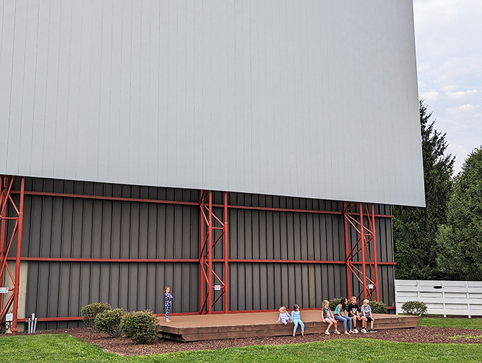 Children gather at the screen's base, creating impromptu playgrounds while waiting for darkness to bring movies to life.