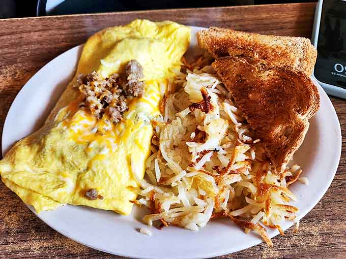 Morning magic on a plate &ndash; a fluffy omelet stuffed with savory fillings alongside golden hash browns and toast ready for butter baptism.