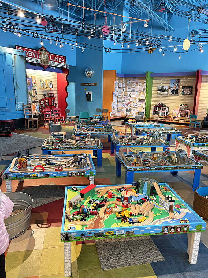 Colorful train tables fill the play area, where strangers become temporary collaborators and track-building challenges unite generations in shared problem-solving.