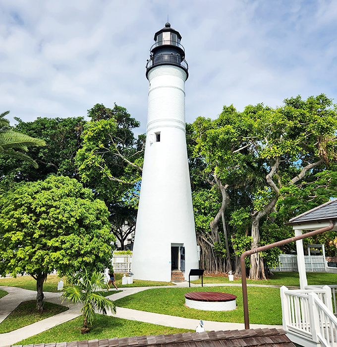 Bathed in daylight, the lighthouse's classic white-and-black design stands in perfect contrast to the vibrant blue Key West sky.