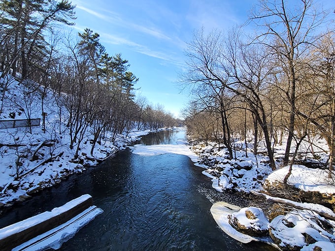 Winter transforms Willow River into a snow-framed ribbon cutting through the frozen landscape, with ice formations clinging to the shoreline.