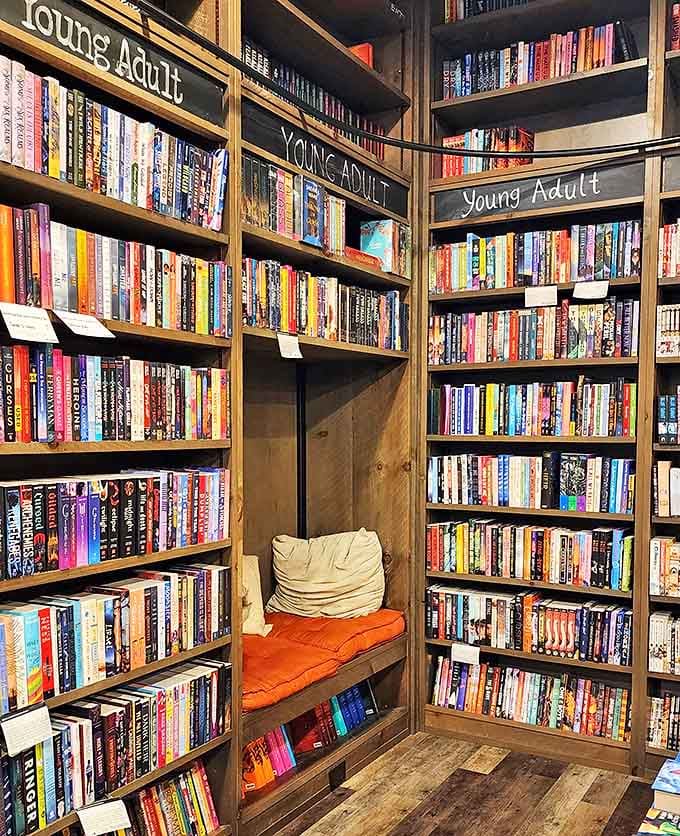 Tucked between towering bookshelves, this reading nook with its orange cushion creates the perfect hideaway for sampling first chapters or finishing just one more page.