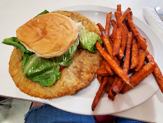 This breaded pork tenderloin sandwich hilariously overwhelms its bun, a Midwest tradition executed with golden-fried perfection.