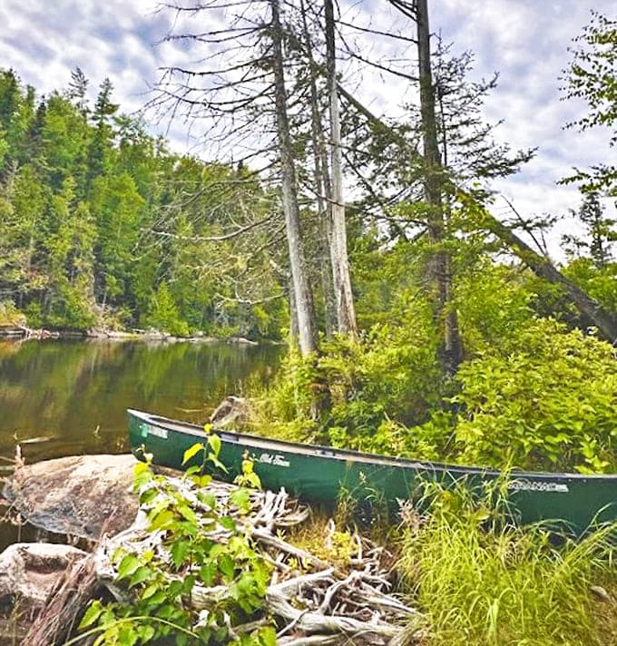 A canoe waits patiently along the riverbank, promising adventures beyond the hiking trail for those willing to explore by water.