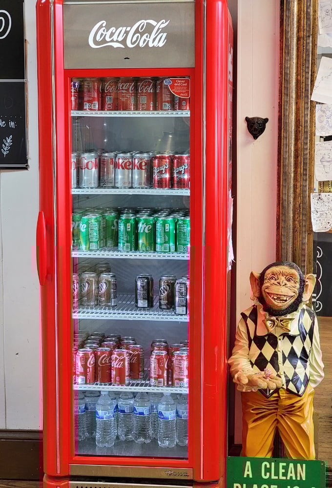 The vintage Coca-Cola cooler stands guard like a sentinel of refreshment, while that monkey figurine seems to know all your dessert secrets.