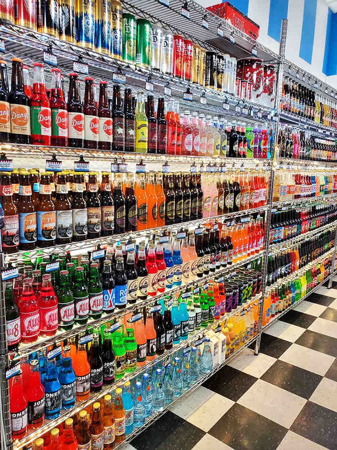 The soda wall features more colors than a painter's palette, each bottle promising carbonated adventures your taste buds never imagined possible.